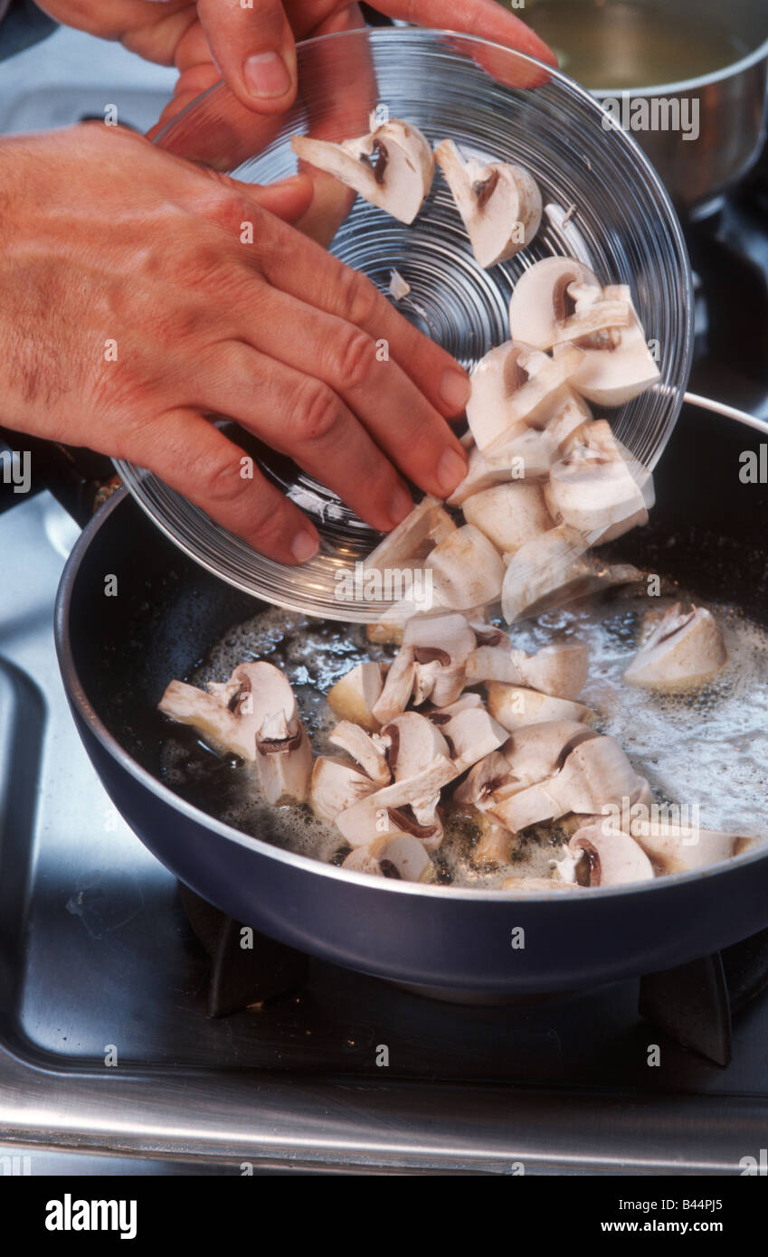 tipping mushrooms into frying pan Stock Photo - Alamy