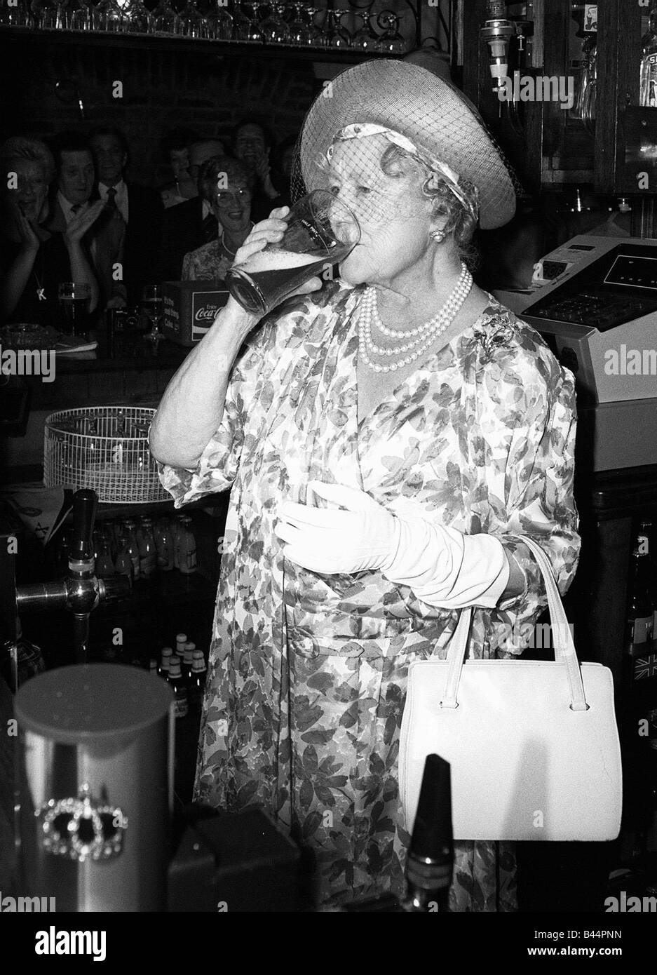 Queen Mother stands behind a pub bar drinking beer in July 1987 Stock ...