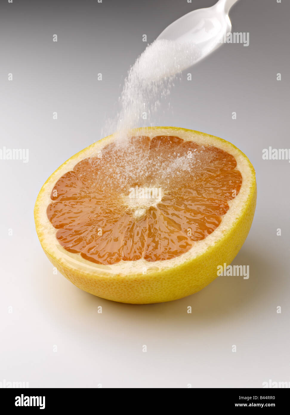 Pouring sugar onto half a grapefruit Stock Photo - Alamy