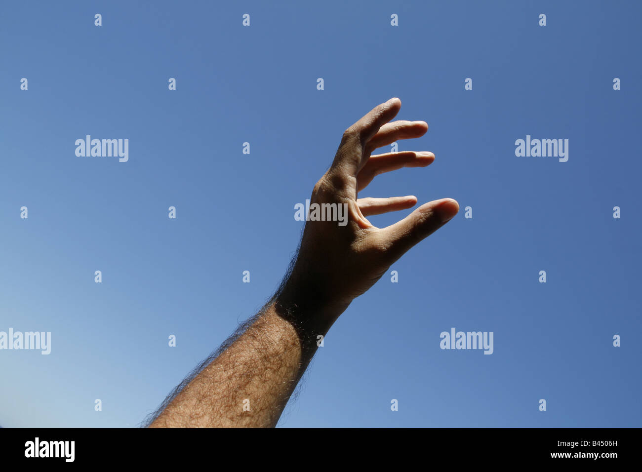 man's hand reaching out into clear blue sky Stock Photo - Alamy