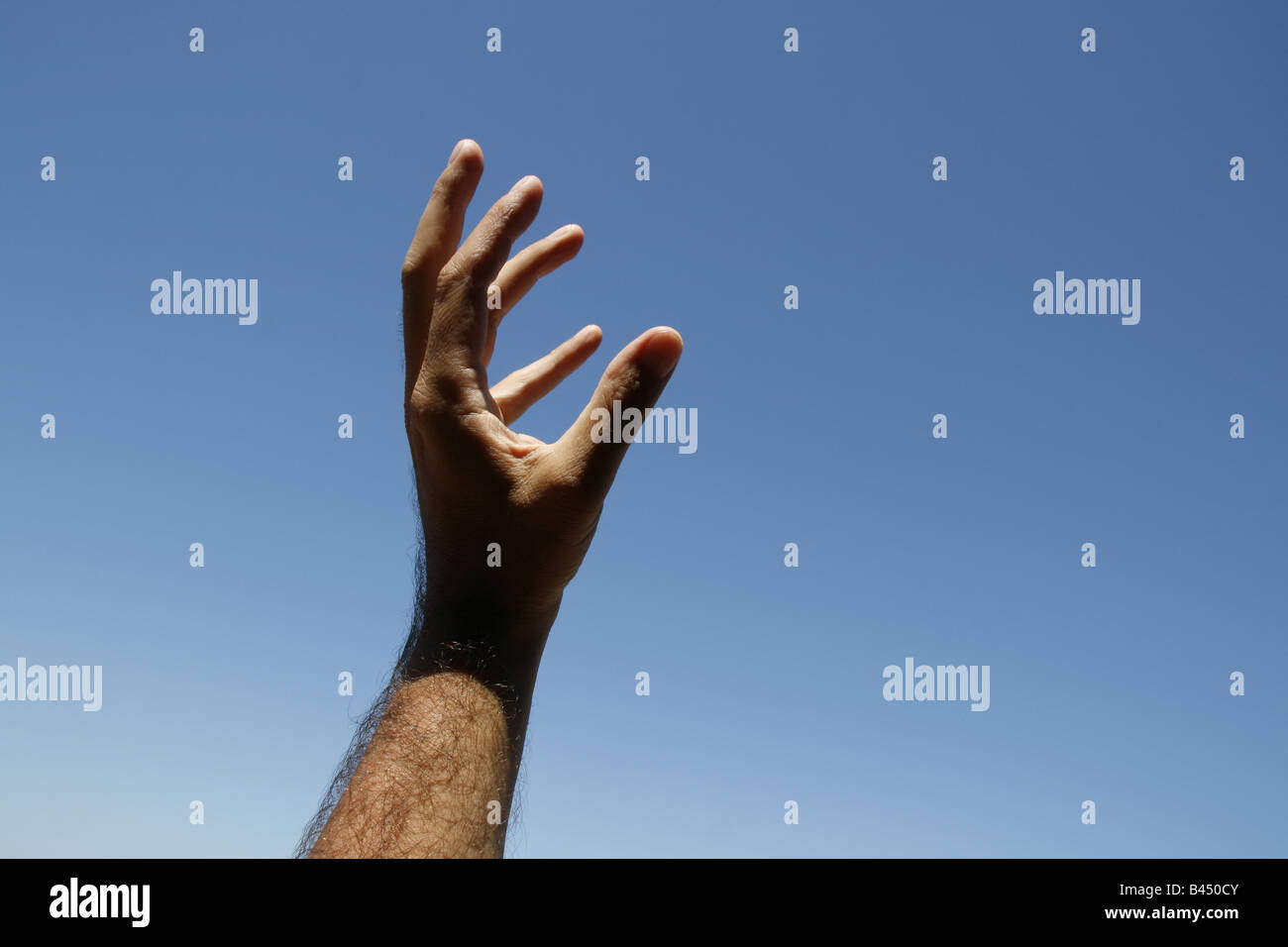 man's hand reaching out into clear blue sky Stock Photo - Alamy