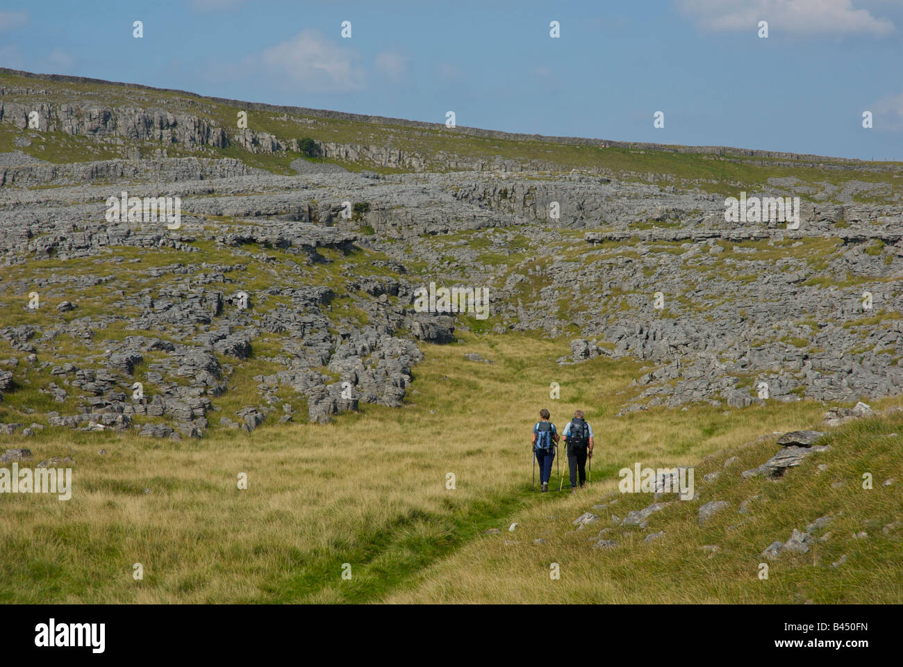 Two people walking towards the extensive limestone pavement at Moughton ...