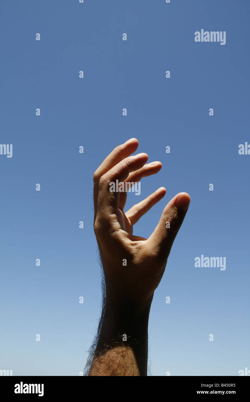 man's hand reaching out into clear blue sky Stock Photo - Alamy