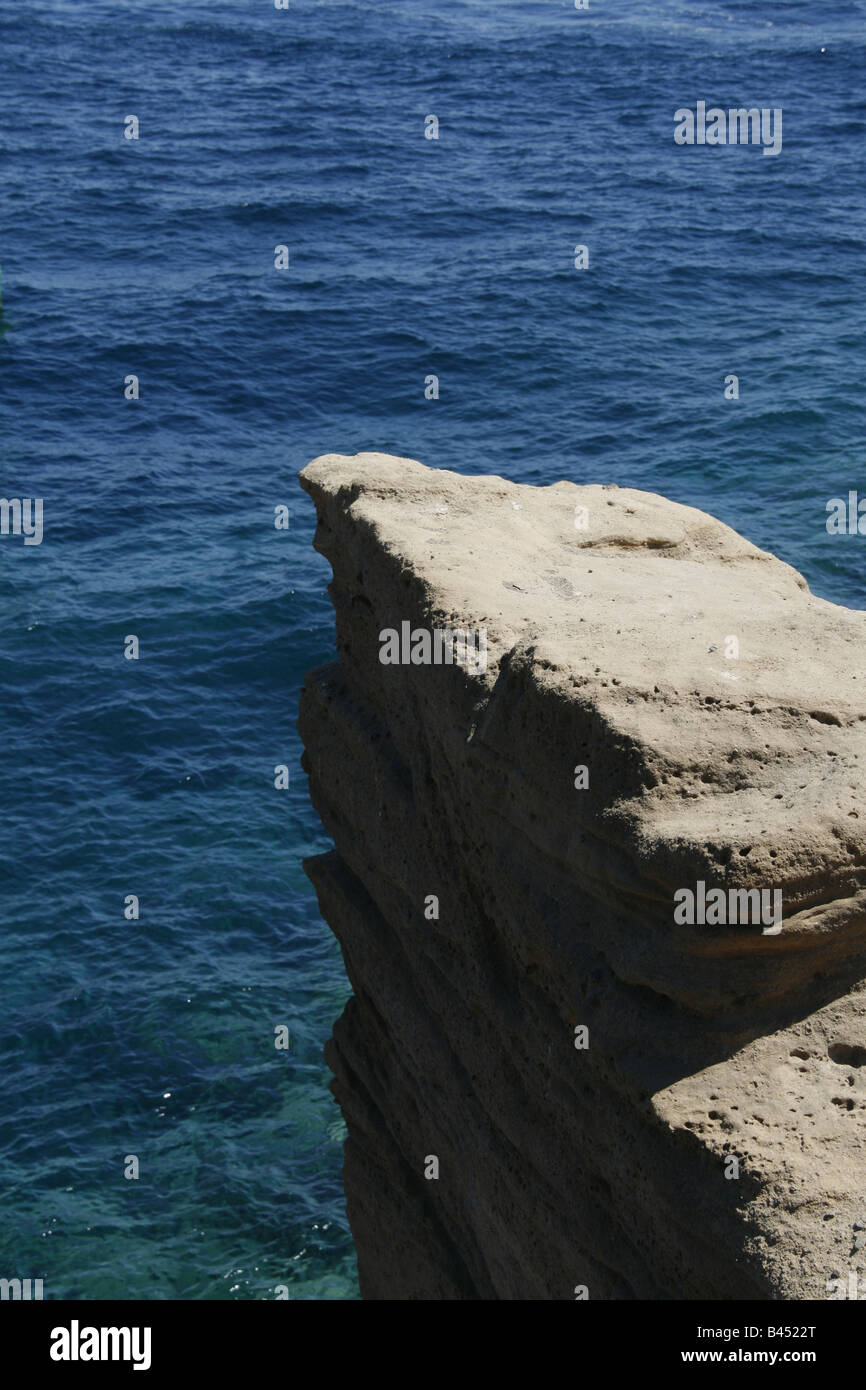 one wild rocky ledge over calm sea waves Stock Photo - Alamy