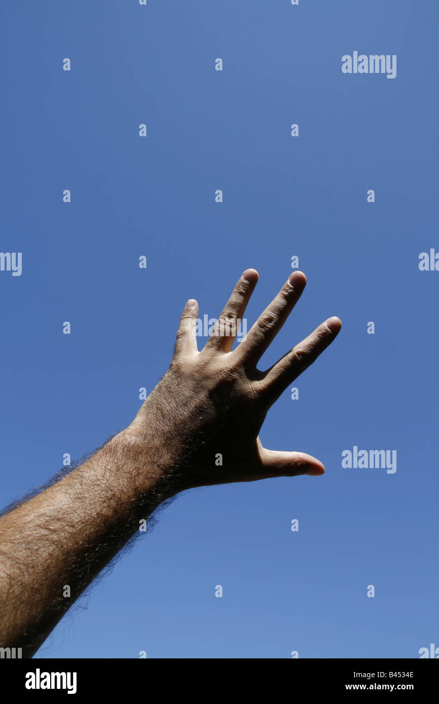 man's hand reaching out into clear blue sky Stock Photo - Alamy