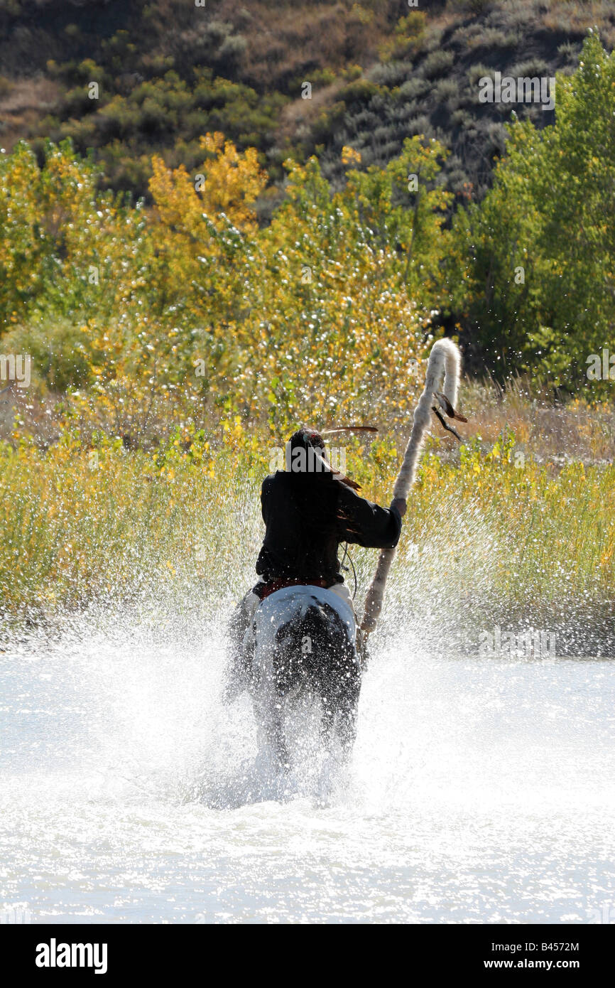 A Native American Sioux Indian on horseback riding across a river on ...