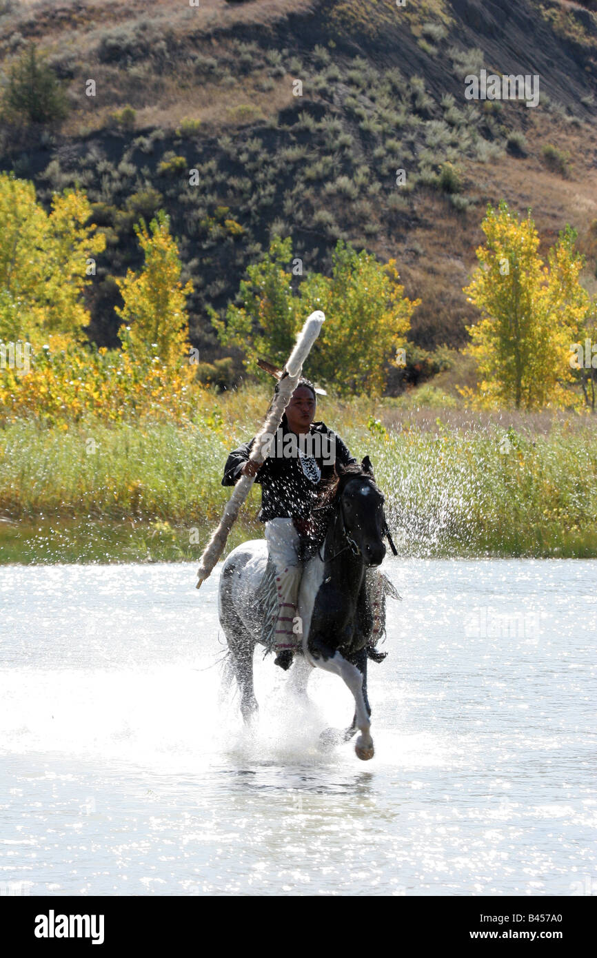 A Native American Sioux Indian on horseback riding across a river on ...
