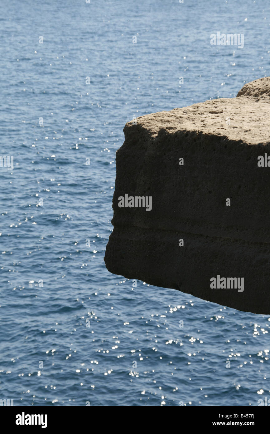 one wild rocky ledge over calm sea waves Stock Photo - Alamy