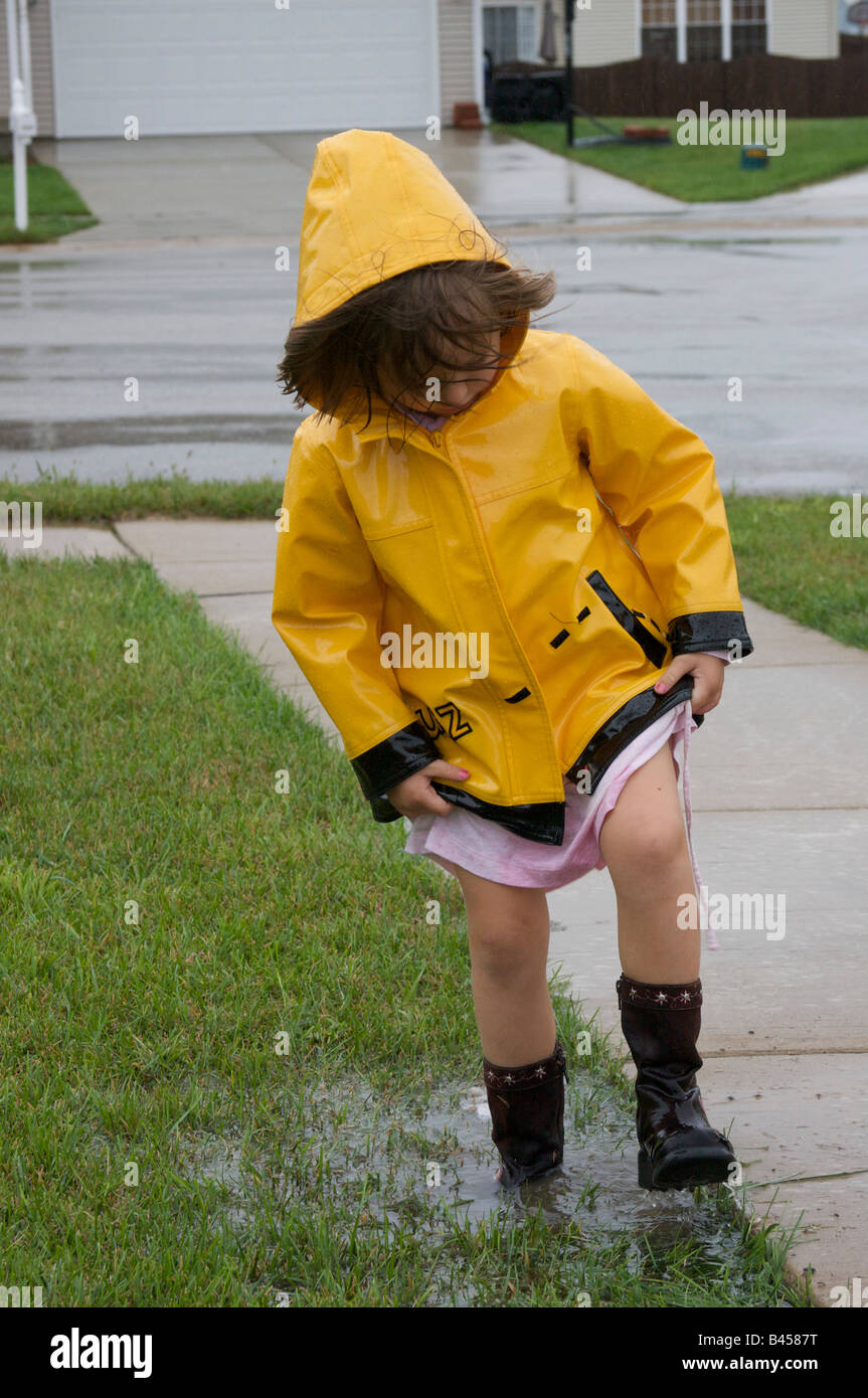 Young girl in rain coat standing in puddle Stock Photo - Alamy