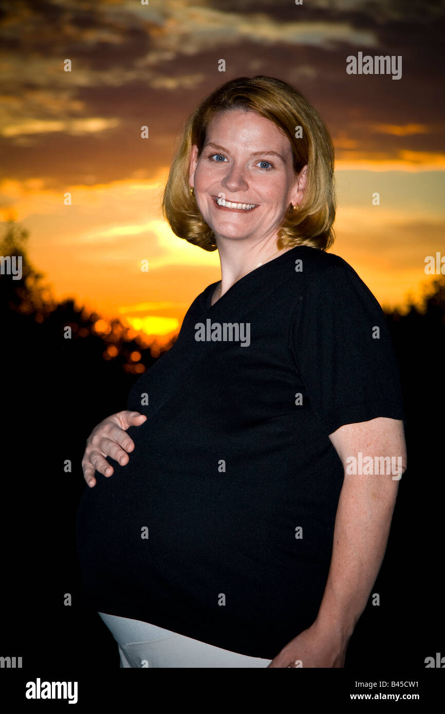 Expectant mother standing in front of sunset Stock Photo - Alamy
