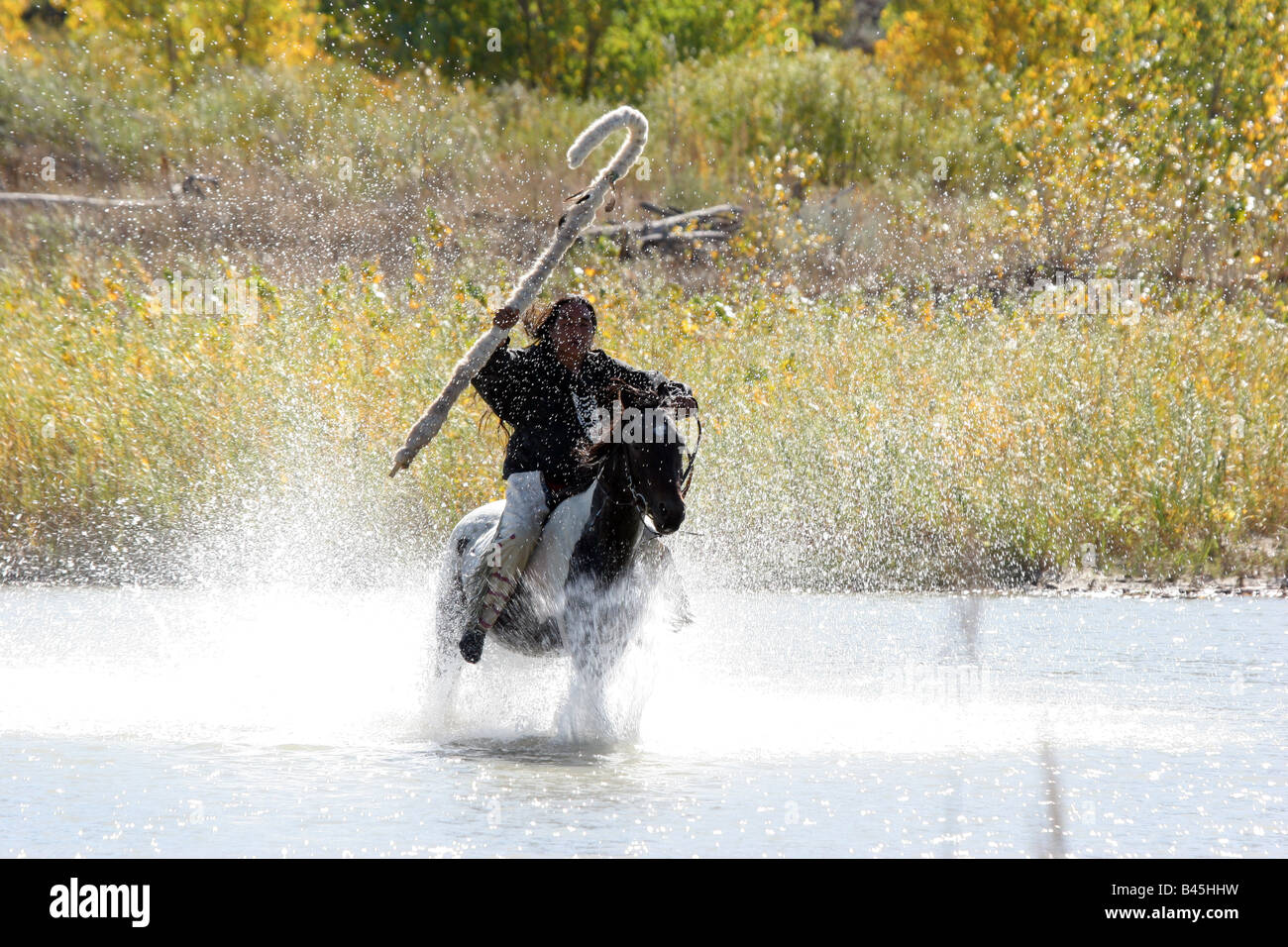 A Native American Sioux Indian on horseback riding across a river on ...