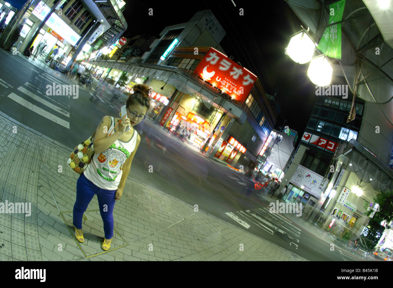 A young Japanese girl talking on her cell phone at night in an urban ...