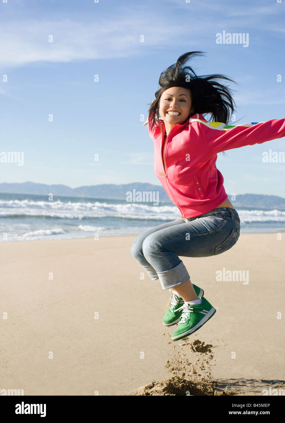 Asian woman jumping on beach Stock Photo - Alamy