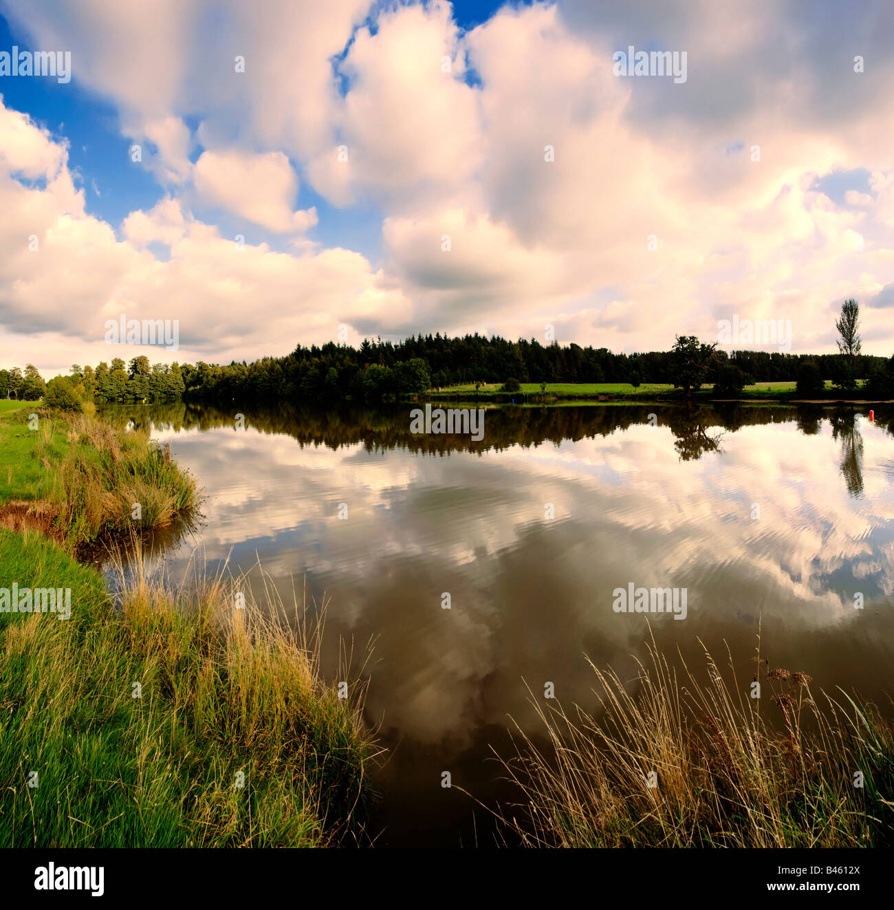 cumulo nimbus clouds at sunset reflected in a lake Stock Photo - Alamy
