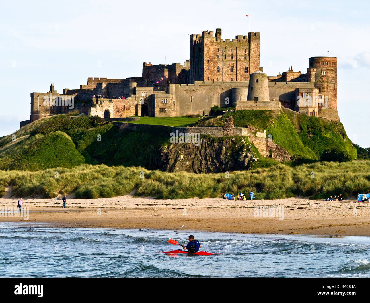 View of Bamburgh beach and castle on a sunny afternoon a canoe is being ...