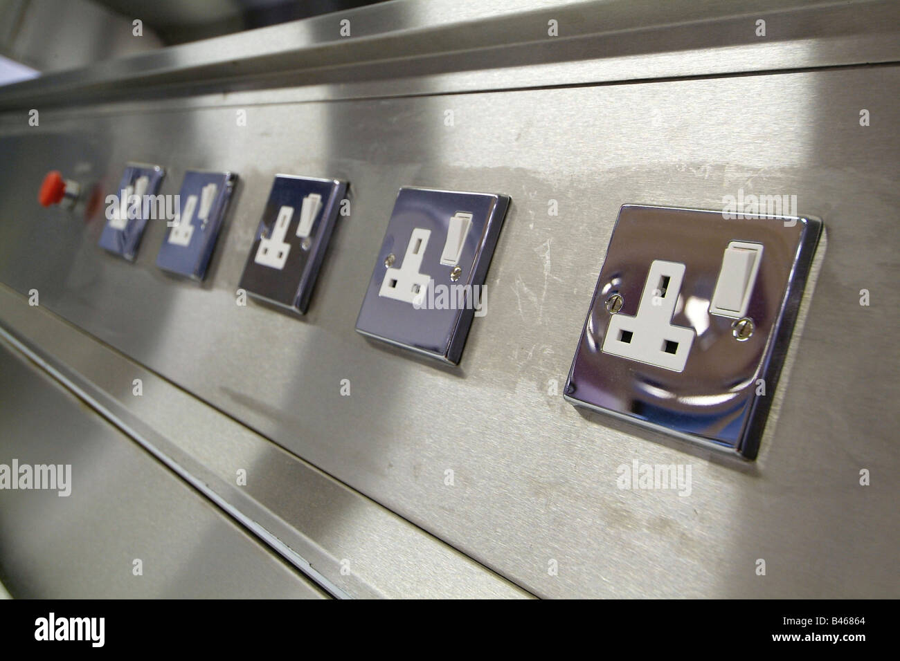 Row of chrome-plated 13amp electrical plug sockets on an office wall ...