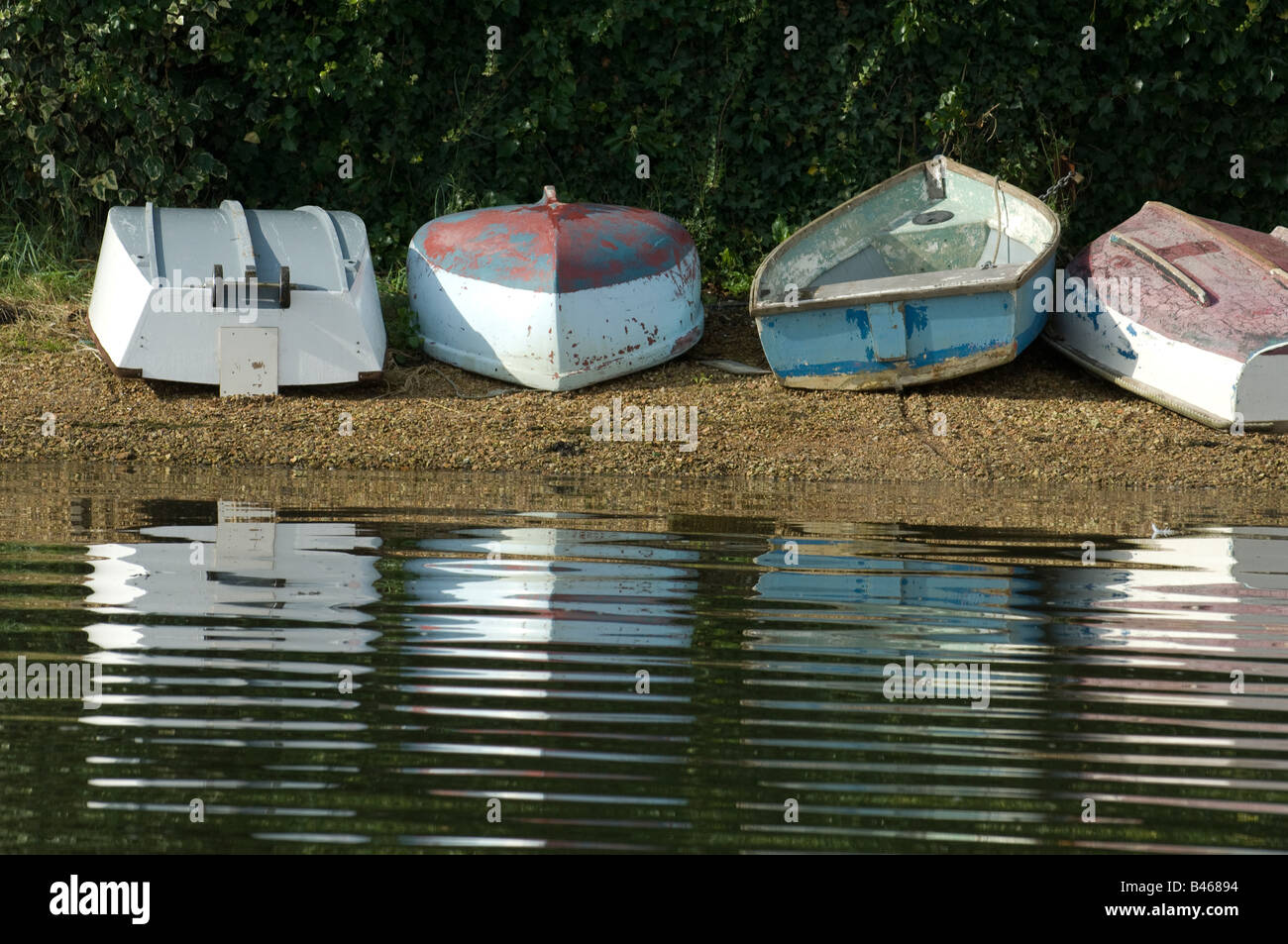 Four dinghies lie on a stoney shore of the Hamble River Hampshire ...