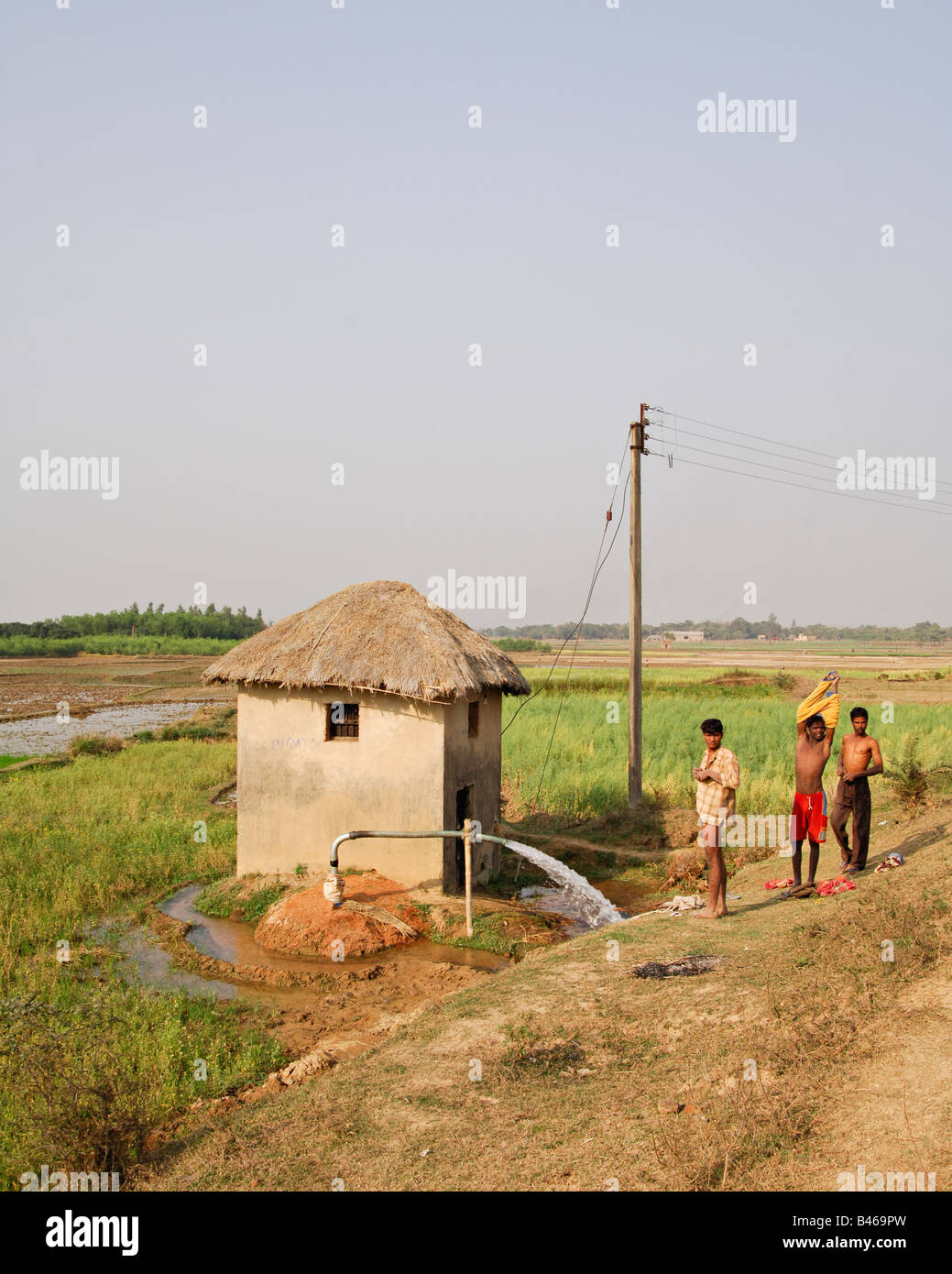 A group of young paddy feild workers prepare to wash at an irrigation ...
