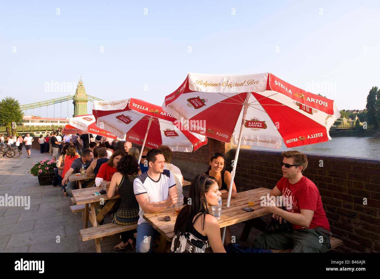 People enjoy a drink on warm summer afternoon in pub by Thames River ...