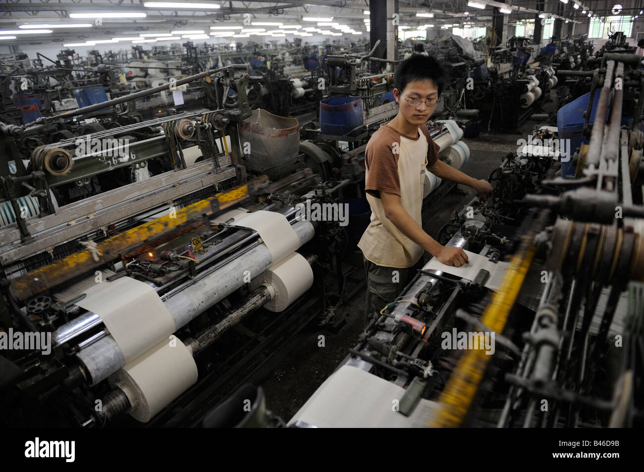 Young worker operating machine at a textile factory in Dongguan ...
