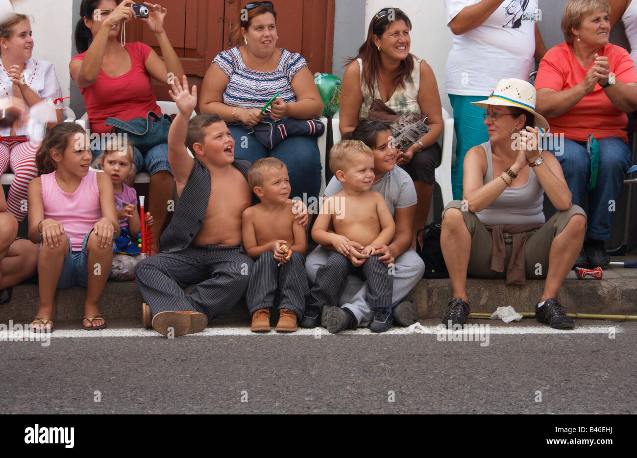 Spanish children sitting at roadside watching parade of floats and ...