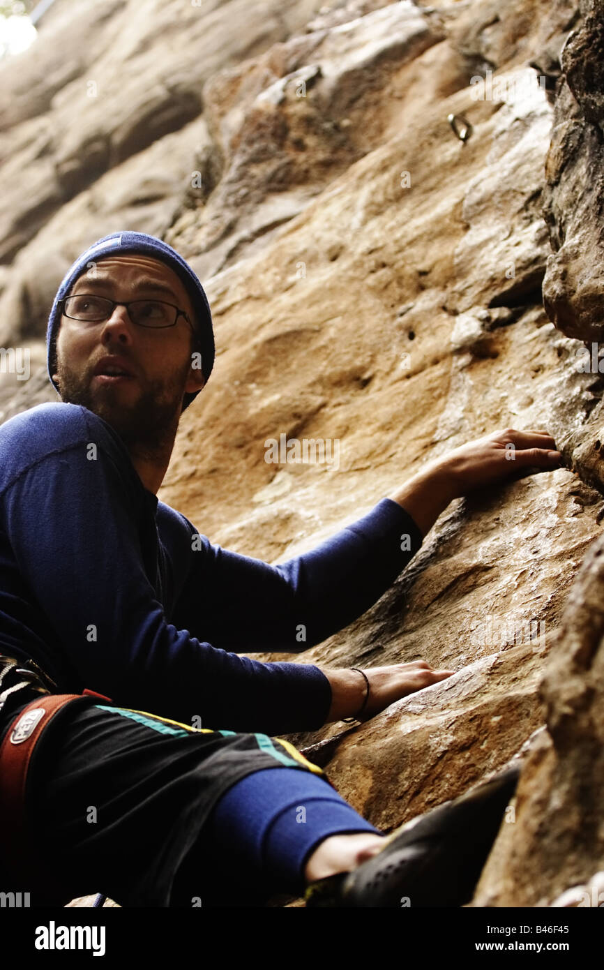Rock climber looking back as he is leading the pitch on a fixed rope ...
