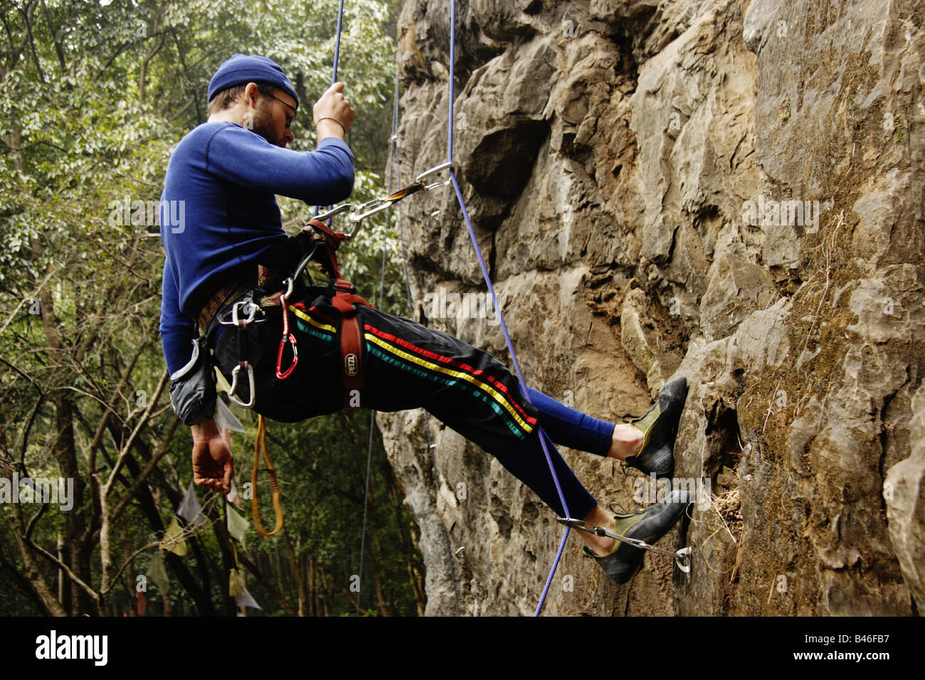 Climber taking a break while scaling a vertical cliff wall in Nepal ...