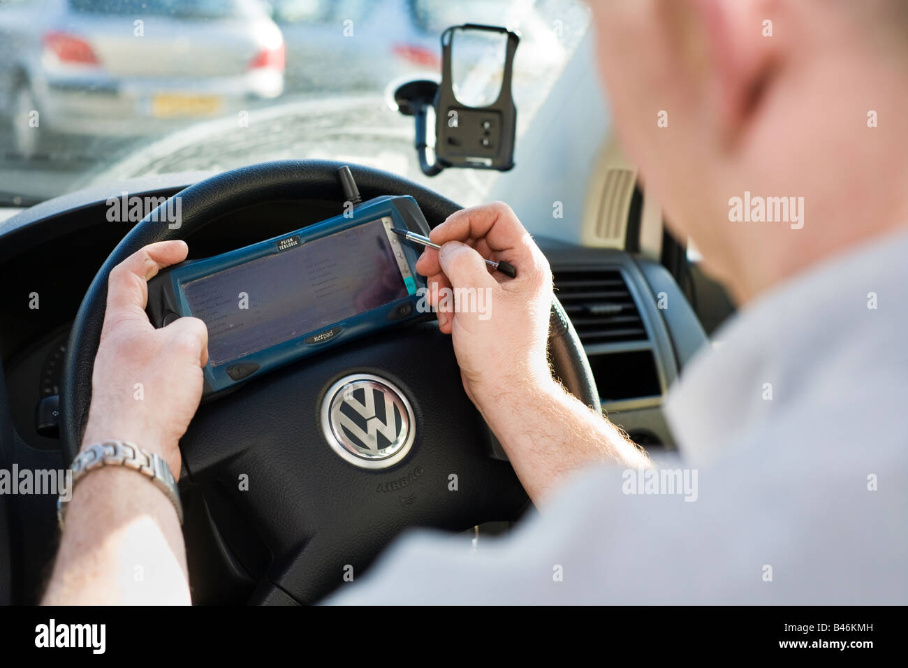 Mobile engineer using a small psion pda portable computer in his van ...