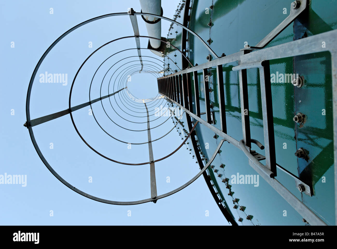 Upward view of a ladder and safety cage on the side of a grain silo ...