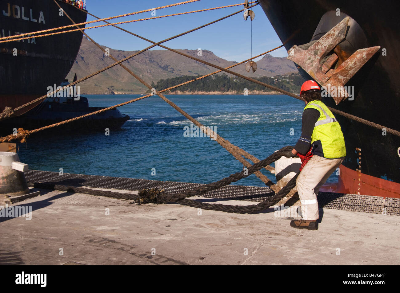 A stevedore assists with placing the mooring lines of a ship that has ...