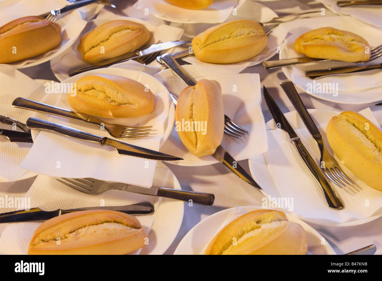 Bread rolls, forks, knives, on plates on a table Stock Photo - Alamy