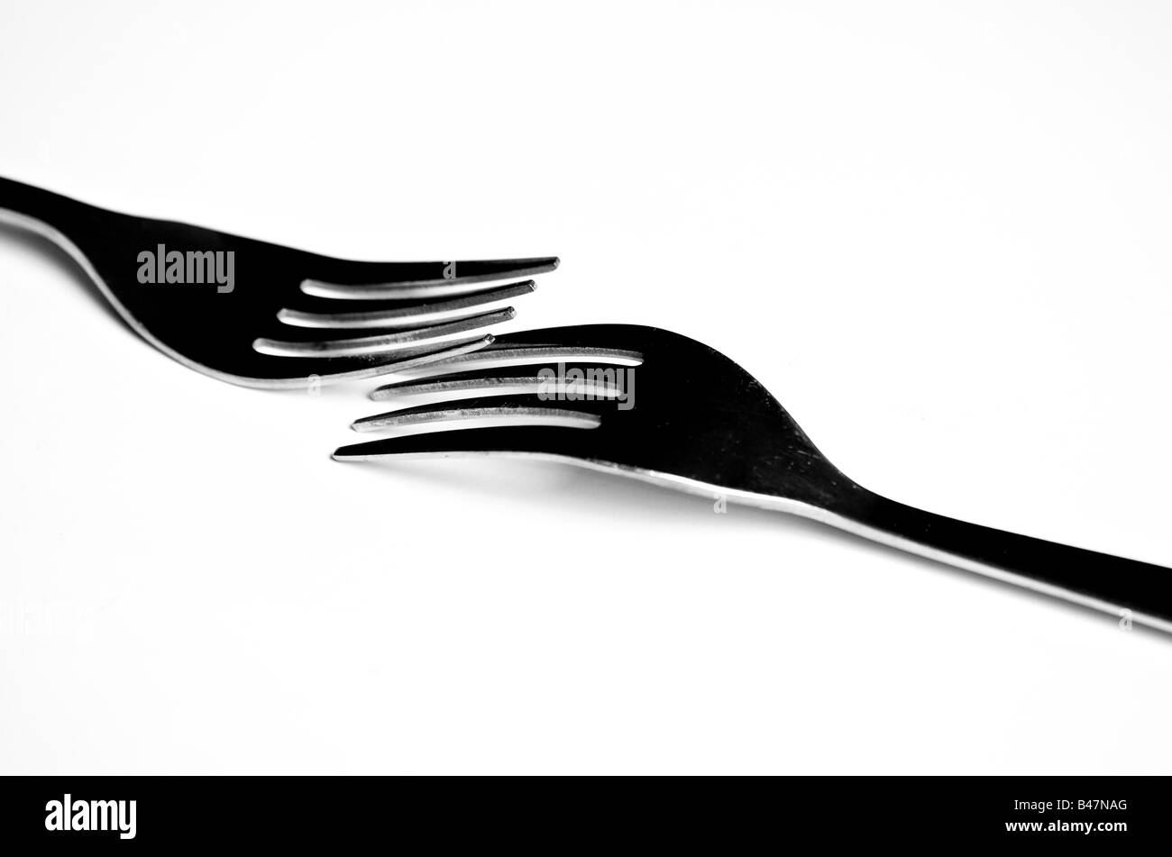 two forks facing on a white table overlapping Stock Photo - Alamy