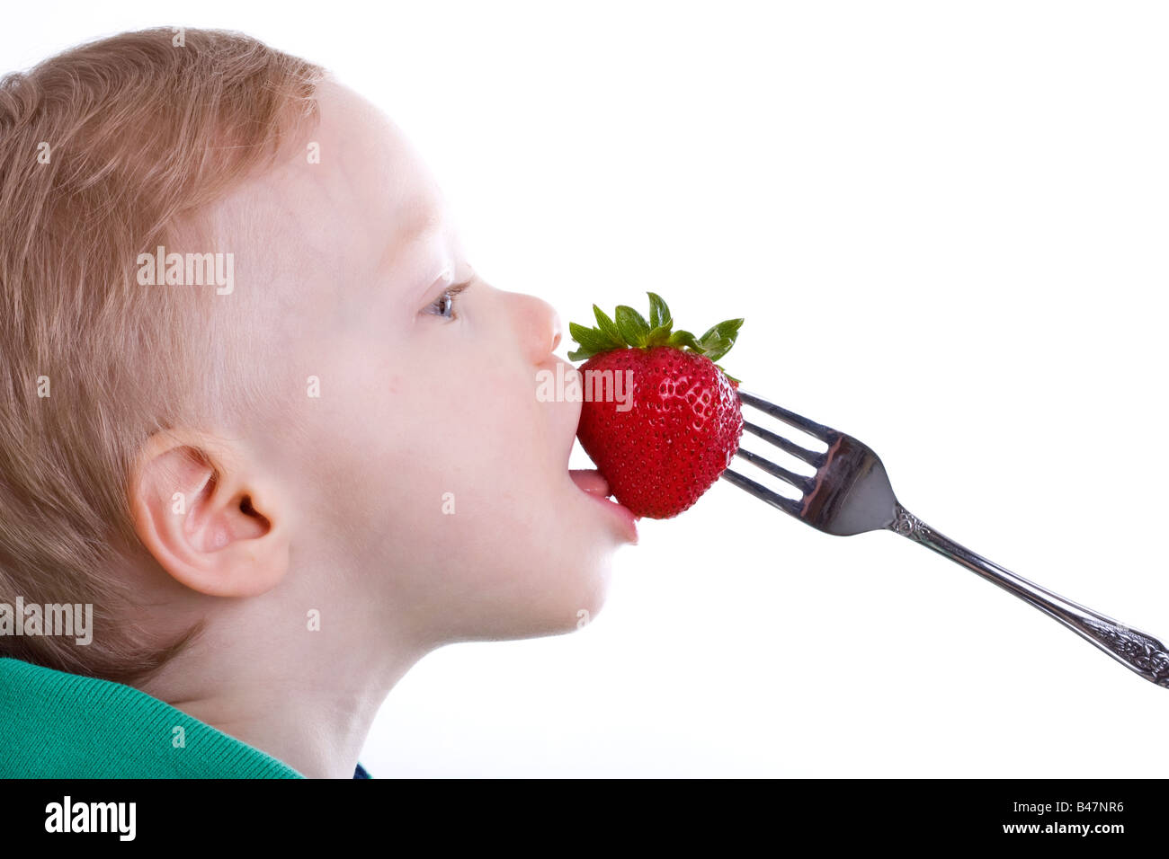 Boy eating strawberry on a fork Stock Photo - Alamy