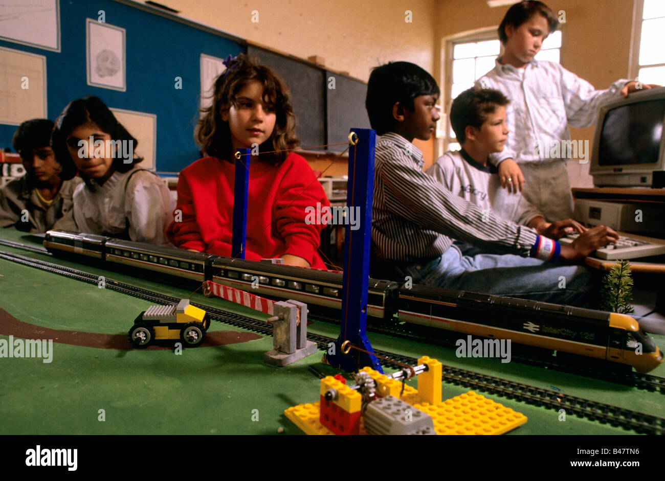 Children watch a toy train go down the track, its progress controlled ...