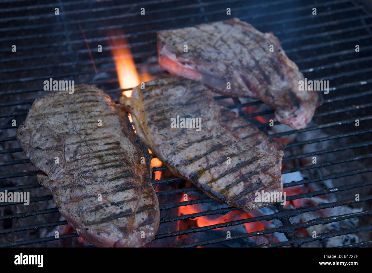 Three steaks grilling over charcoal Stock Photo - Alamy