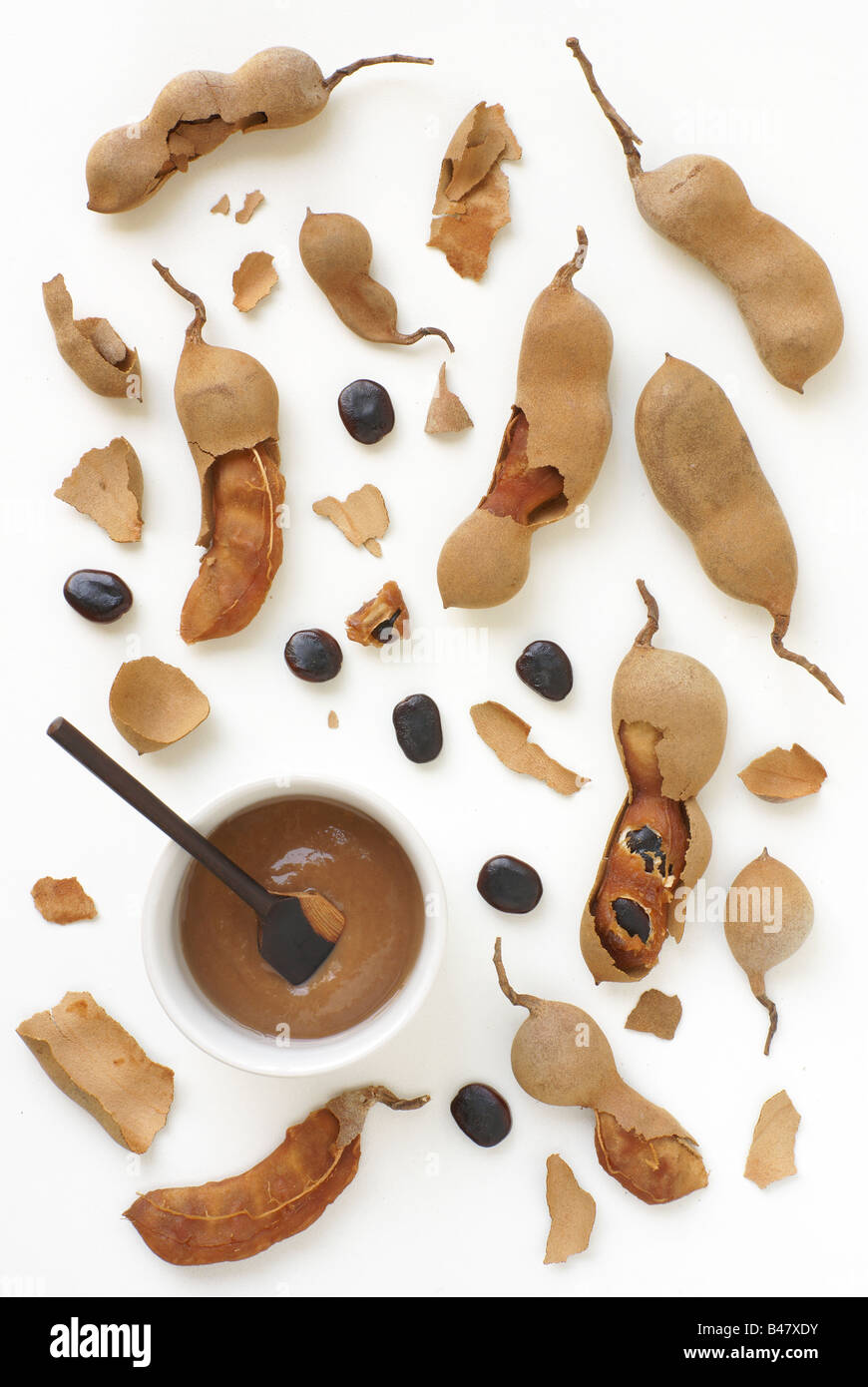 a bowl of tamarind sauce with tamarind fruits on a white background ...