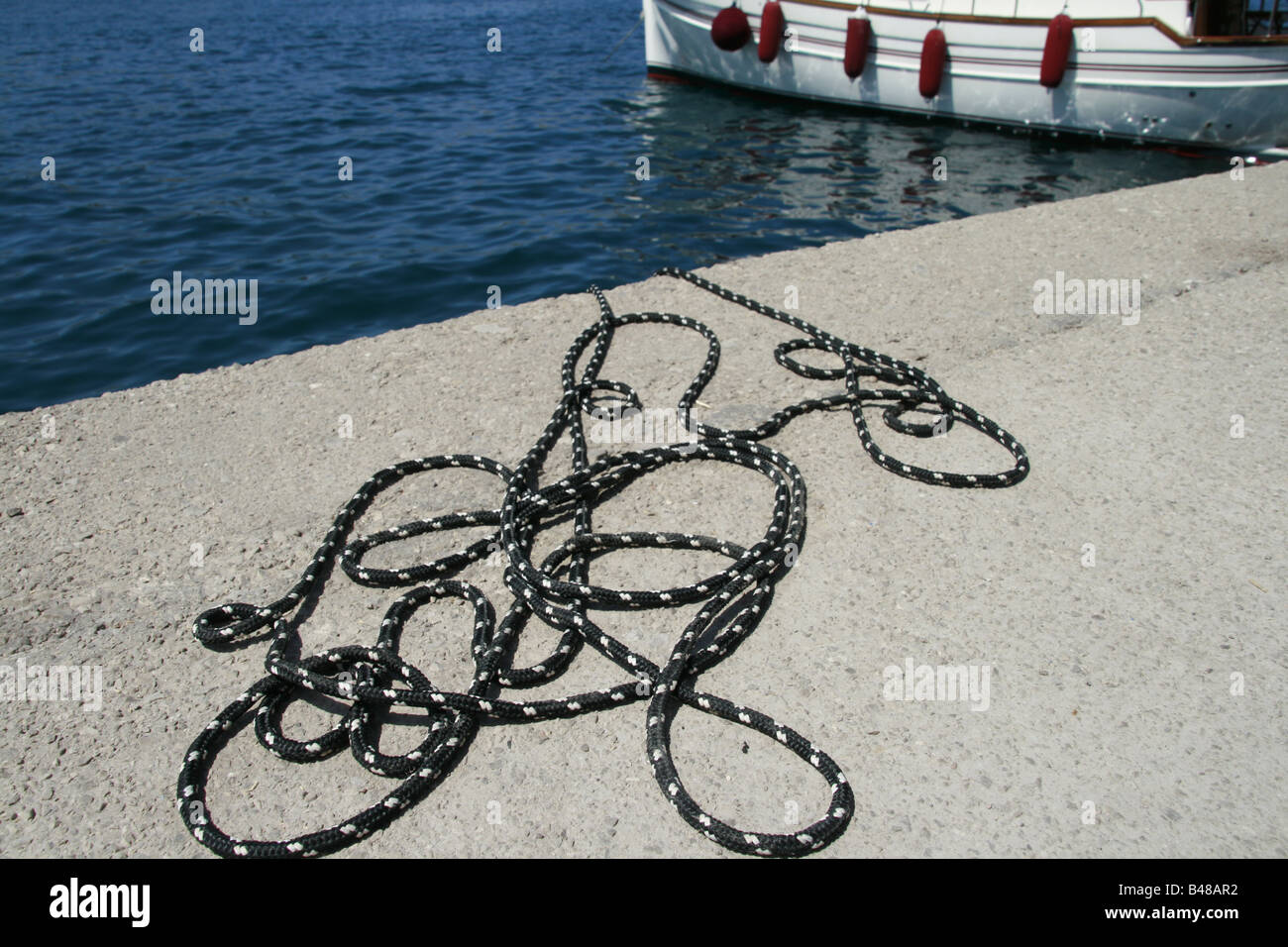 coil of tangled boat mooring rope in harbour Stock Photo - Alamy