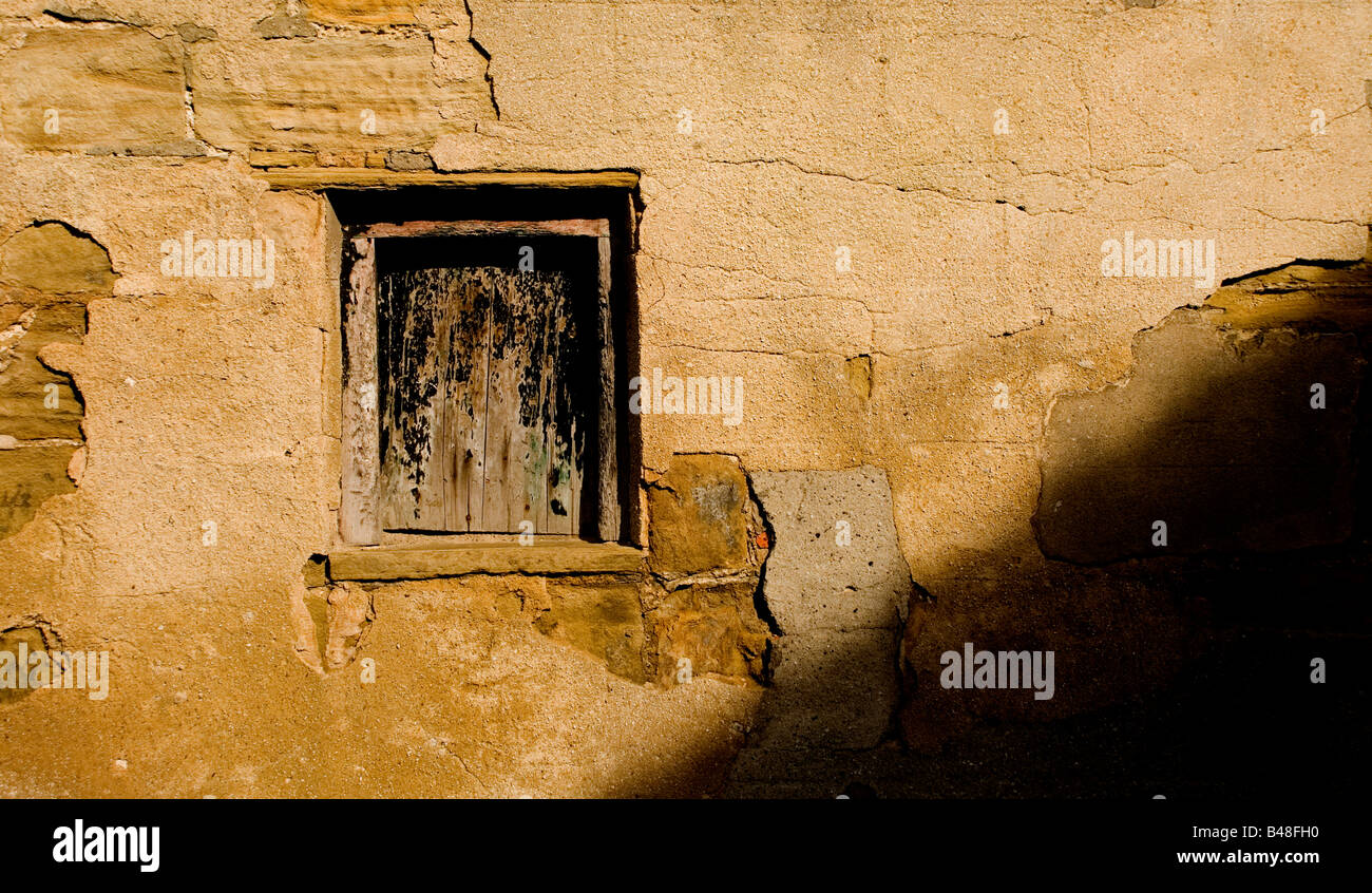 A rotting wooden window frame in a decaying plaster wall with bright ...