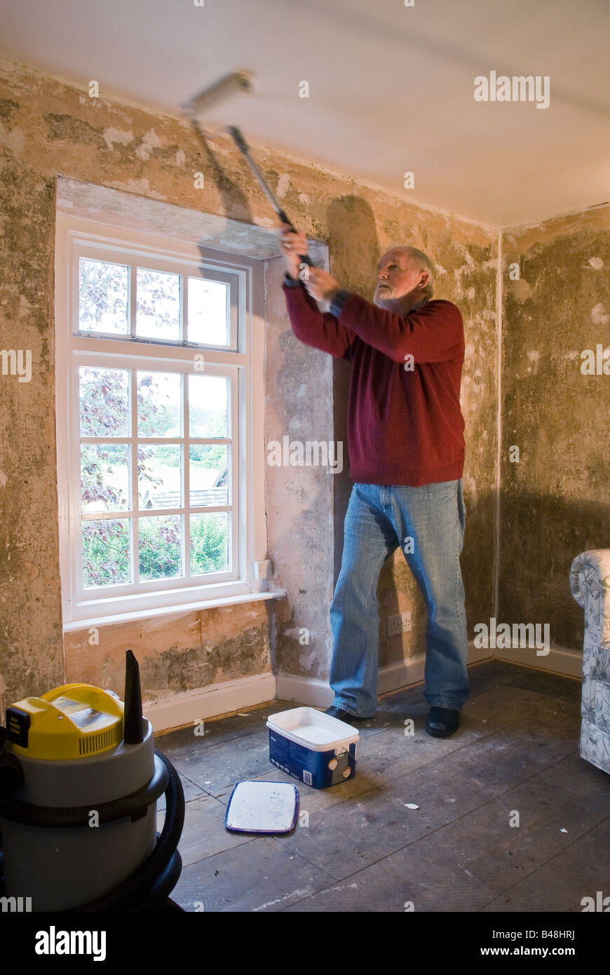 Older man painting ceiling in old cottage UK Stock Photo - Alamy