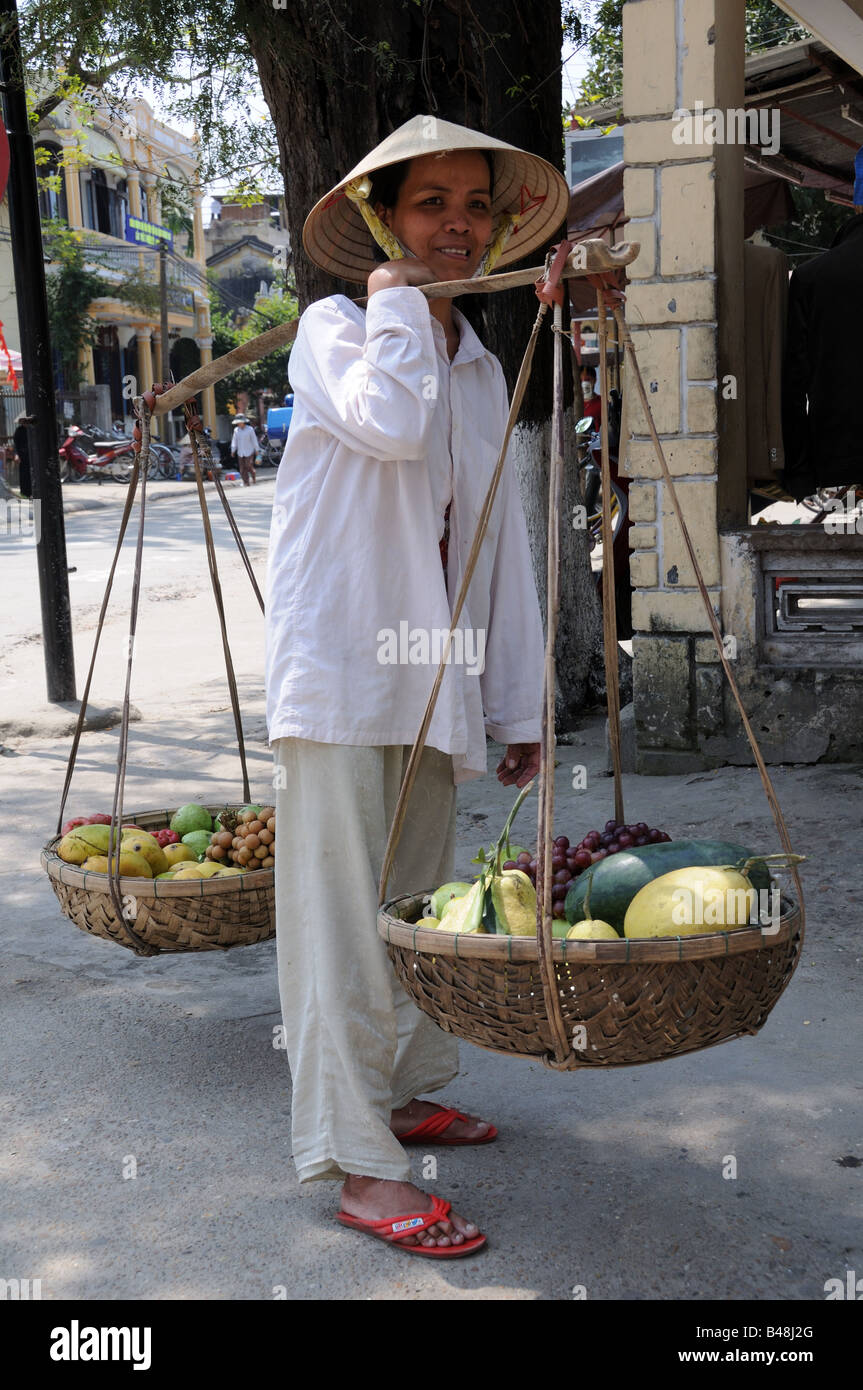 Vietnamese woman street trader selling fruit from traditional baskets ...