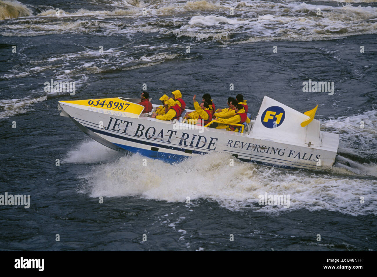A jet boat filled with passengers rides the rapids of Reversing Falls ...