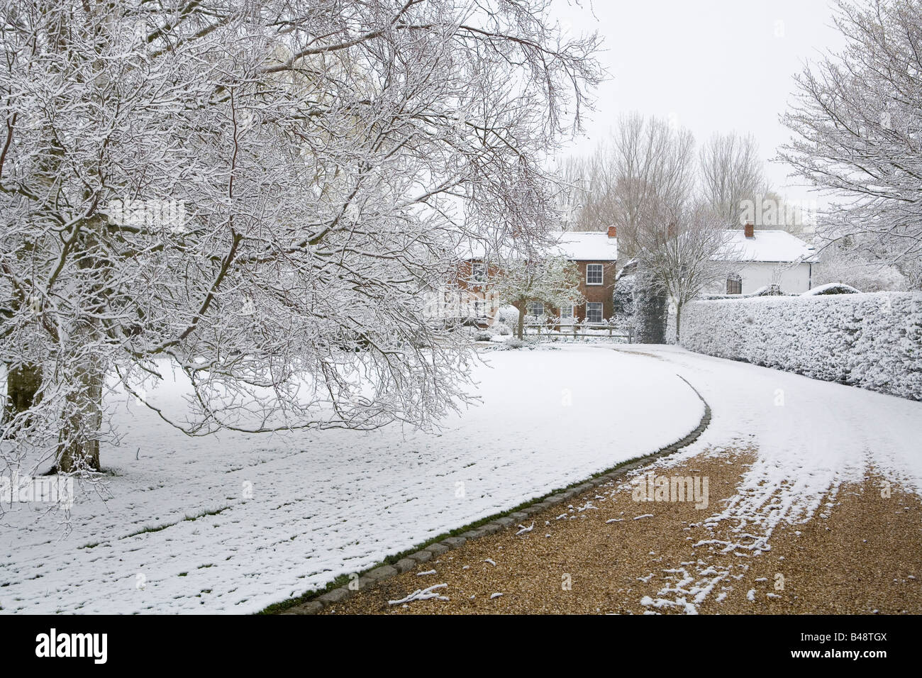 driveway leading up to house with garden and trees covered in snow ...