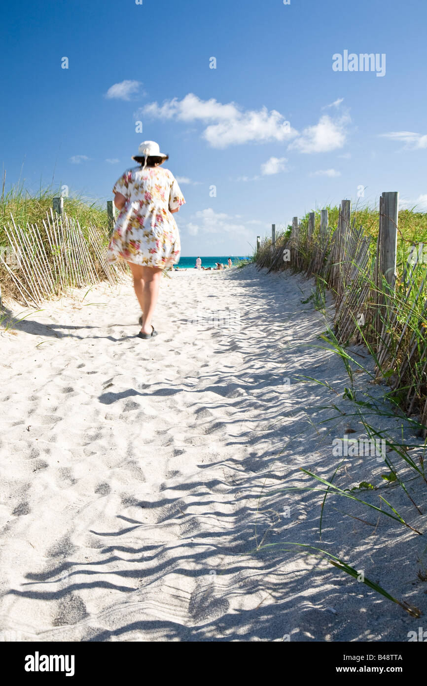 A woman walking along a sandy beach path Stock Photo - Alamy