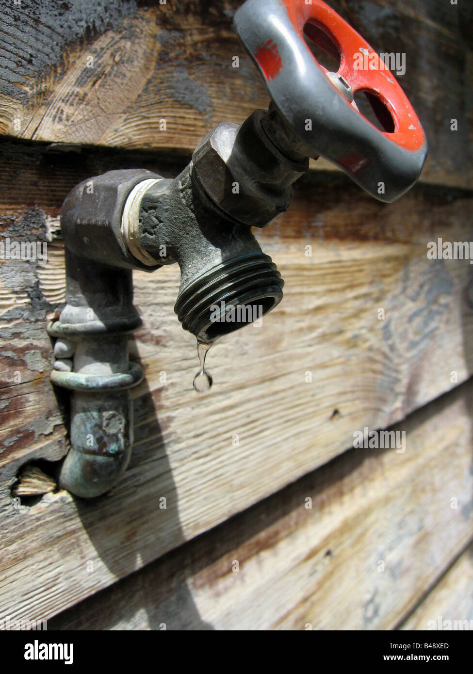 Dripping leaky tap attached to the side of a wooden wall Stock Photo ...