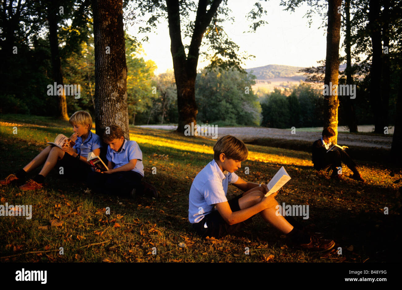 Boys sitting under the trees and reading their books Stock Photo - Alamy