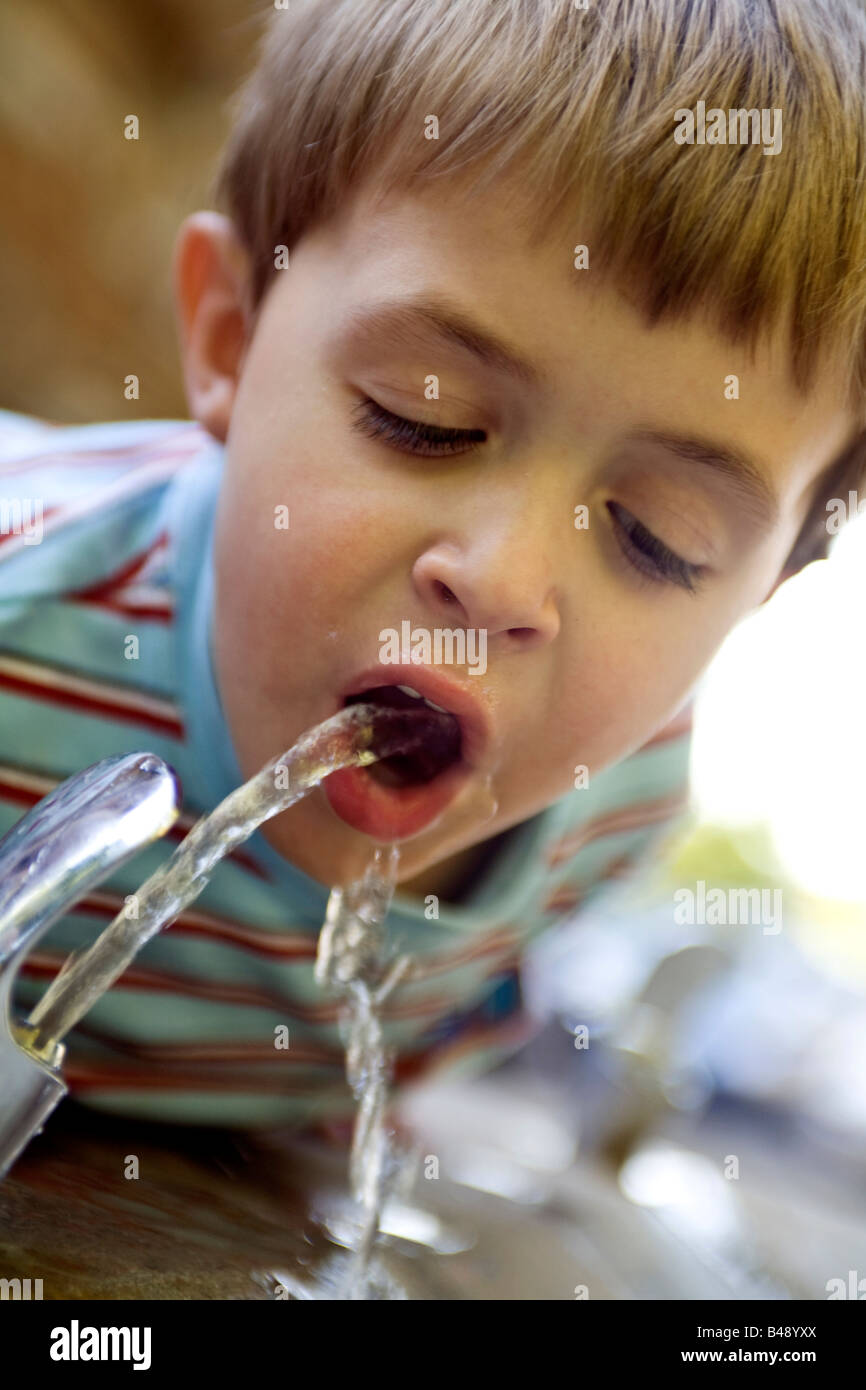 A young boy drinks from the water fountain at the park Stock Photo - Alamy