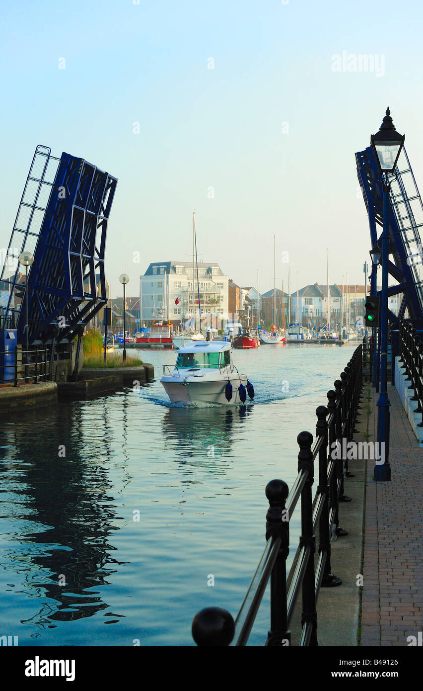 Small fishing boat passes under a bridge in a harbour Stock Photo - Alamy