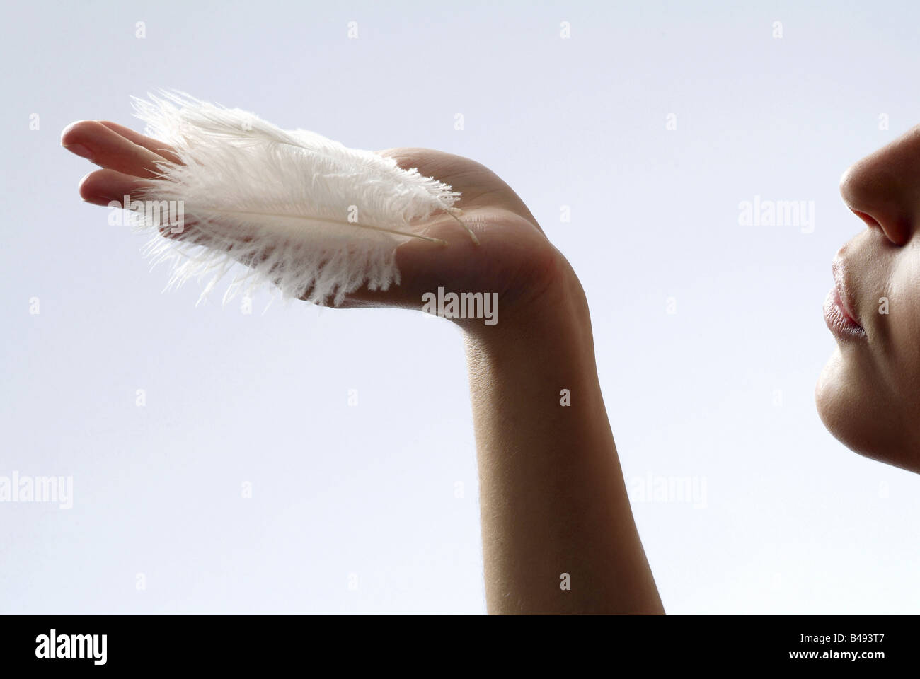 Young woman blowing a feather Stock Photo - Alamy