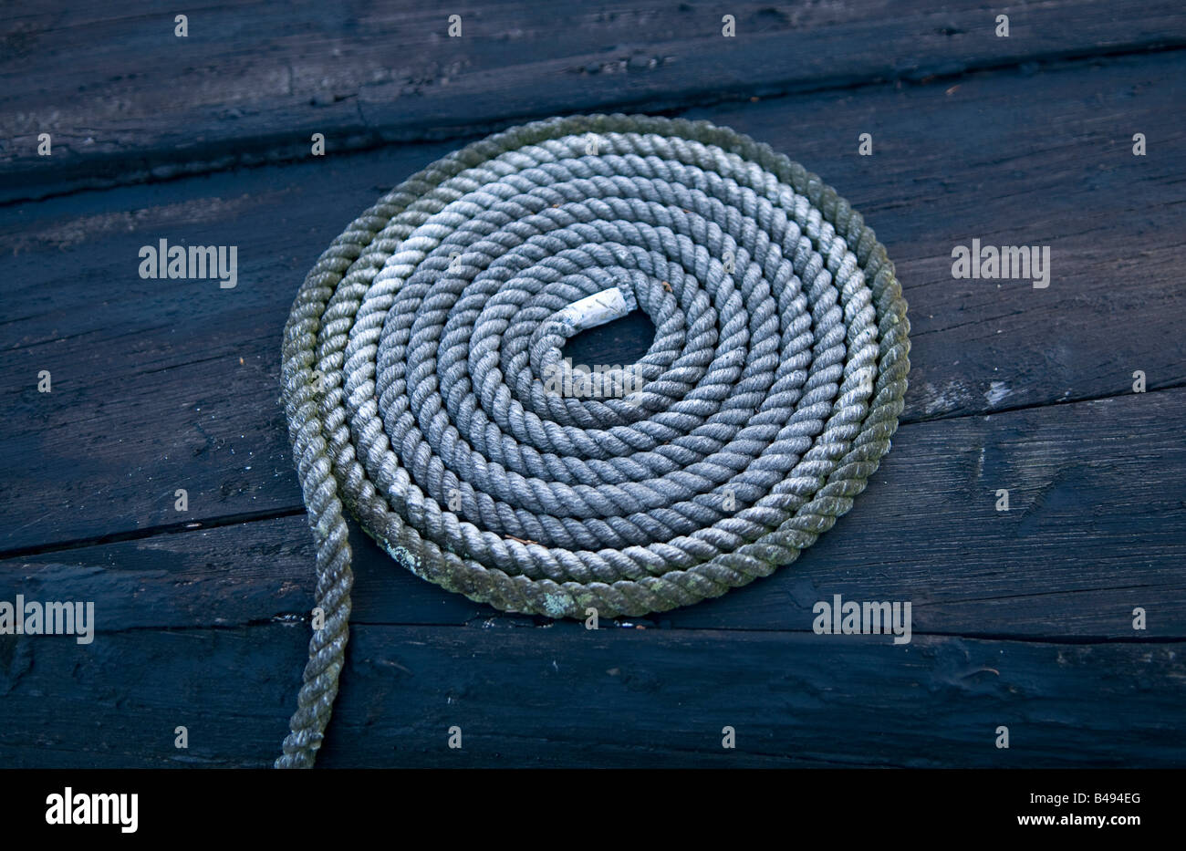 A rope neatly rolled up on a tared boat Stock Photo - Alamy