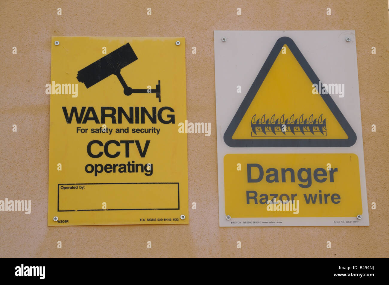 Security signs warning about CCTV cameras and razor wire on a retail ...